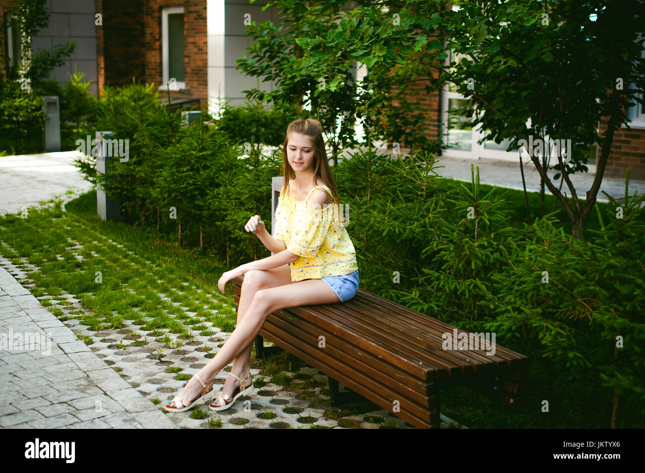 Portrait of a young pretty woman in blue denim jeans shorts sitting on ...