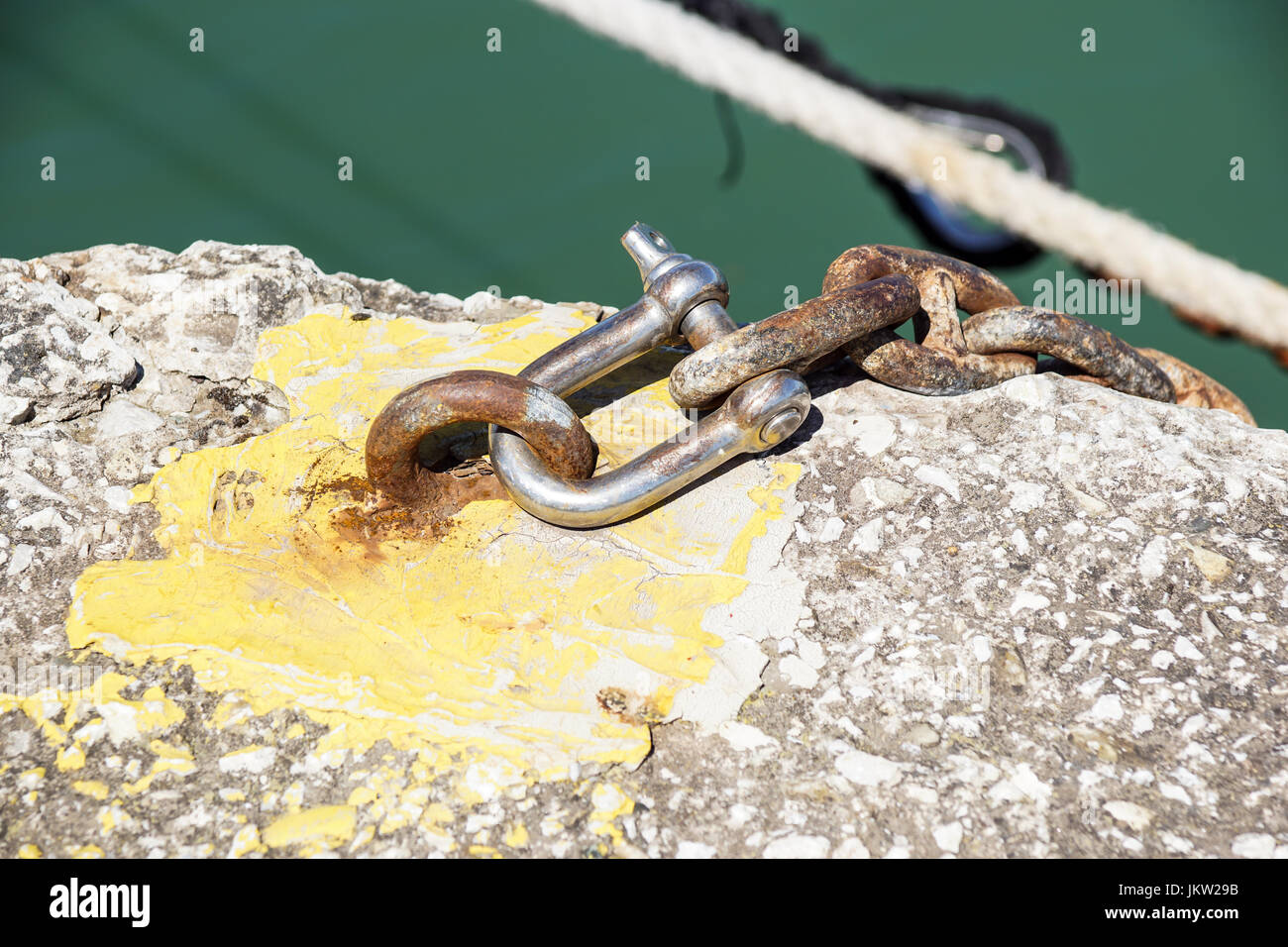 Rusty metal shackle on a metal bar laying on weathered wood outdoors ...