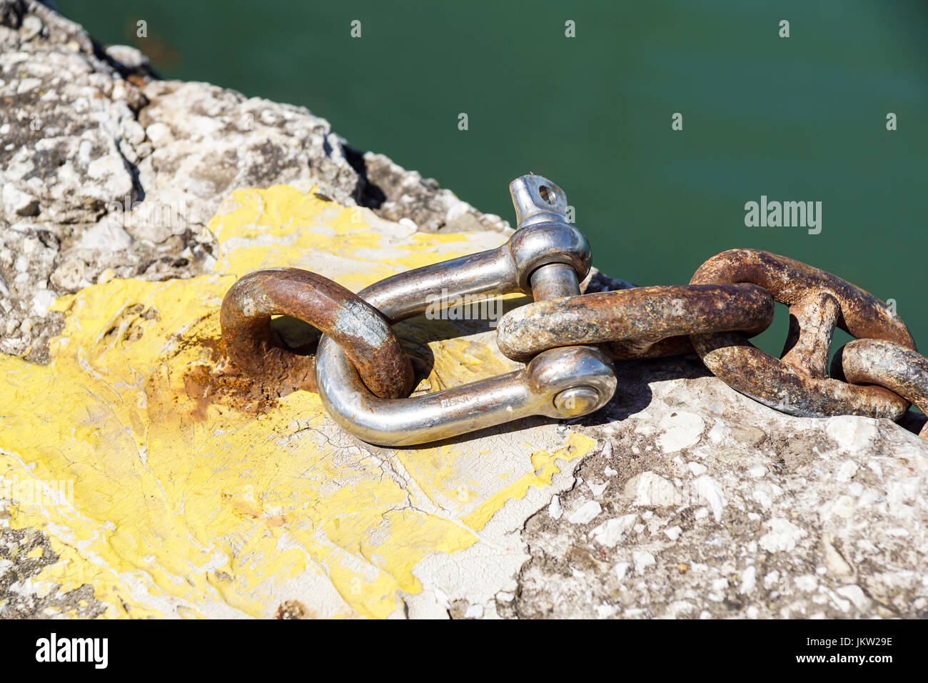 Rusty metal shackle on a metal bar laying on weathered wood outdoors ...