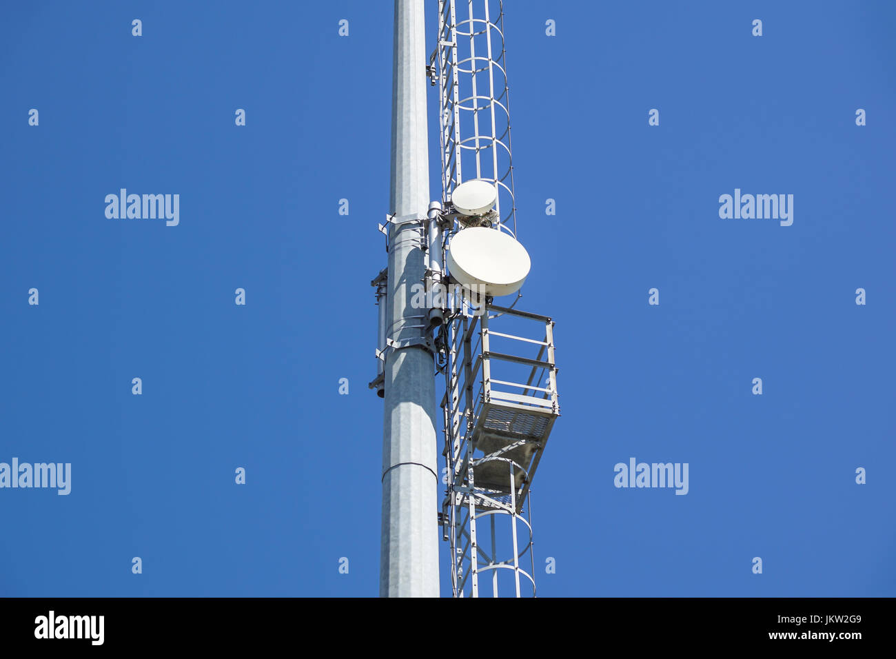 Outdoor stadium lights and telecommunication tower against daytime blue ...