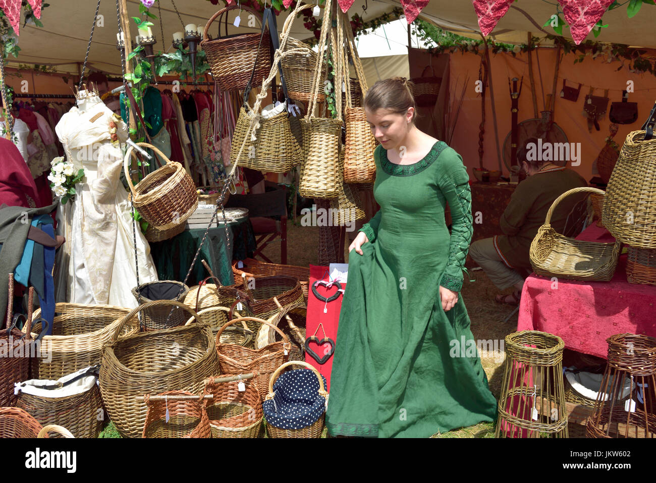 Woman in medieval dress at craft stall selling traditional willow woven ...