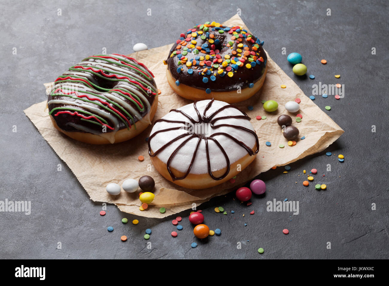 Colorful donuts and candies on stone table Stock Photo - Alamy