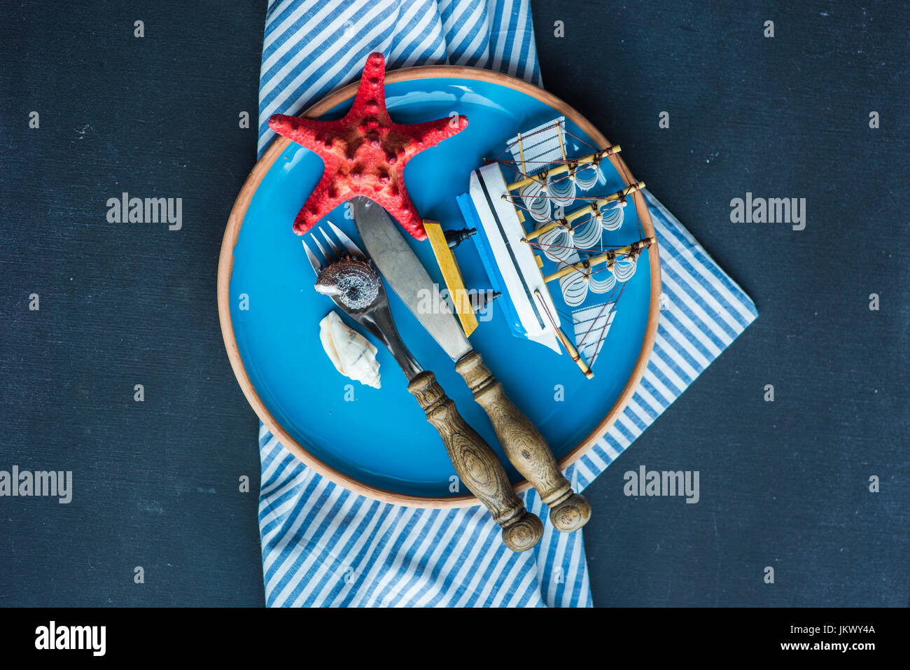 Summer vacation marine table setting with rustic plates and silverware ...
