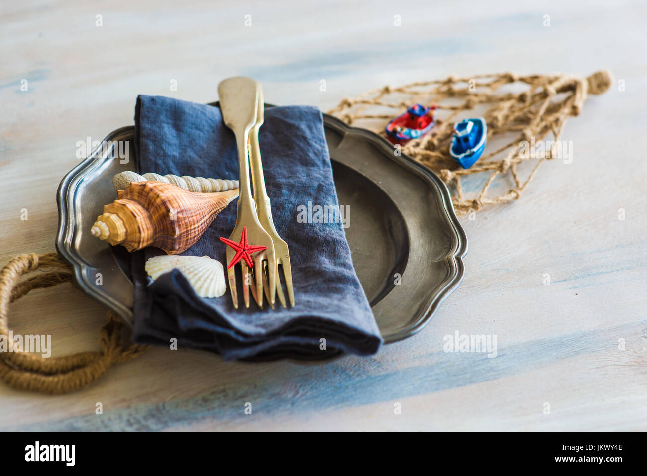 Summer vacation marine table setting with rustic plates and silverware ...
