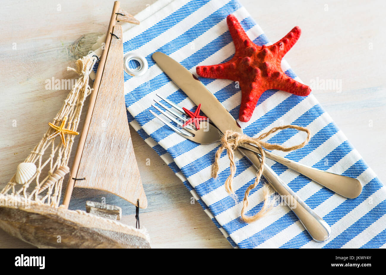 Summer vacation marine table setting with rustic plates and silverware ...