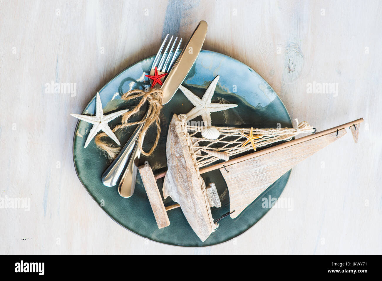 Summer vacation marine table setting with rustic plates and silverware ...