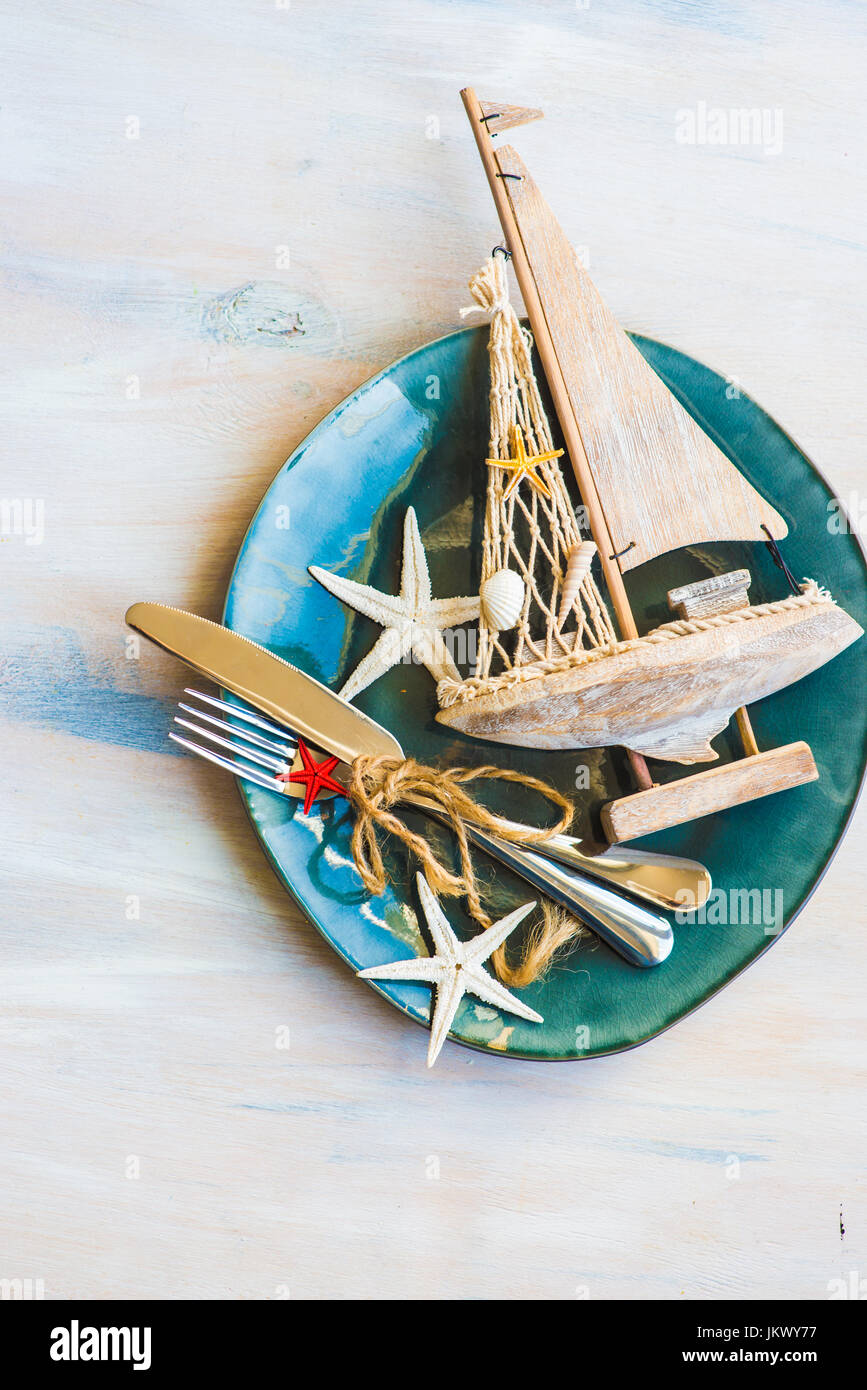 Summer vacation marine table setting with rustic plates and silverware ...