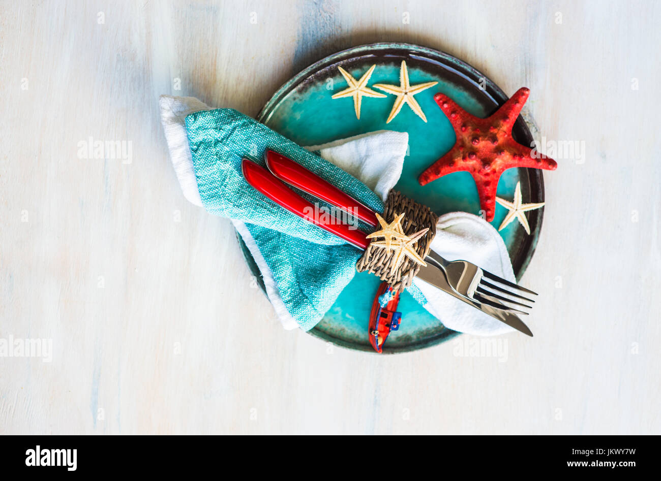 Summer vacation marine table setting with rustic plates and silverware ...