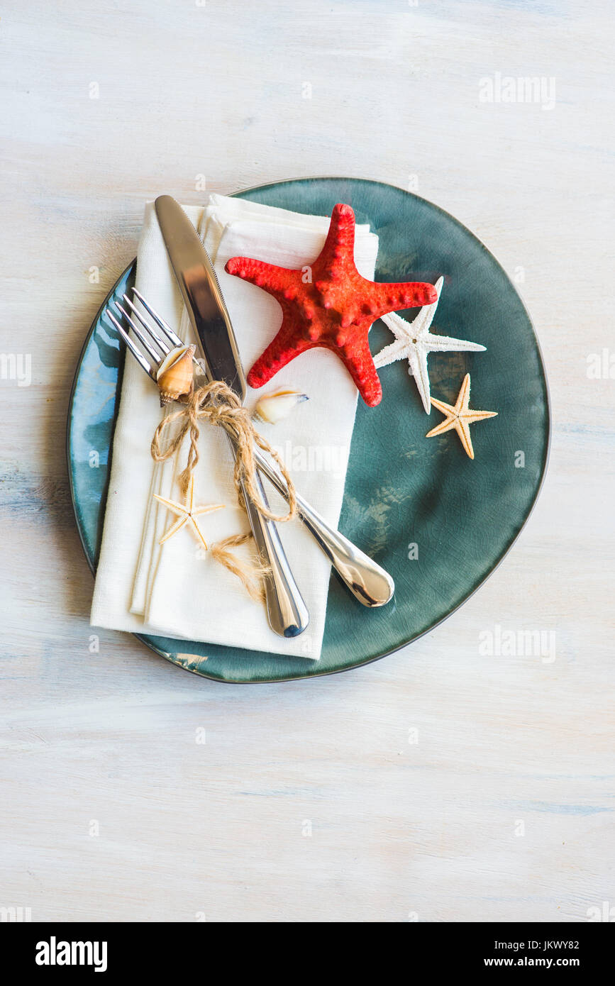 Summer vacation marine table setting with rustic plates and silverware ...