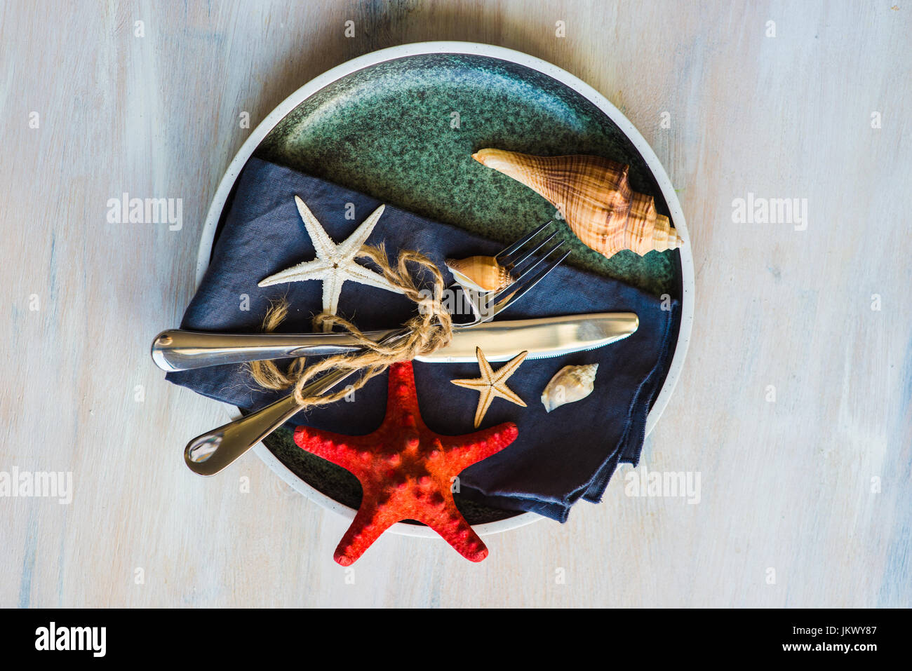 Summer vacation marine table setting with rustic plates and silverware ...