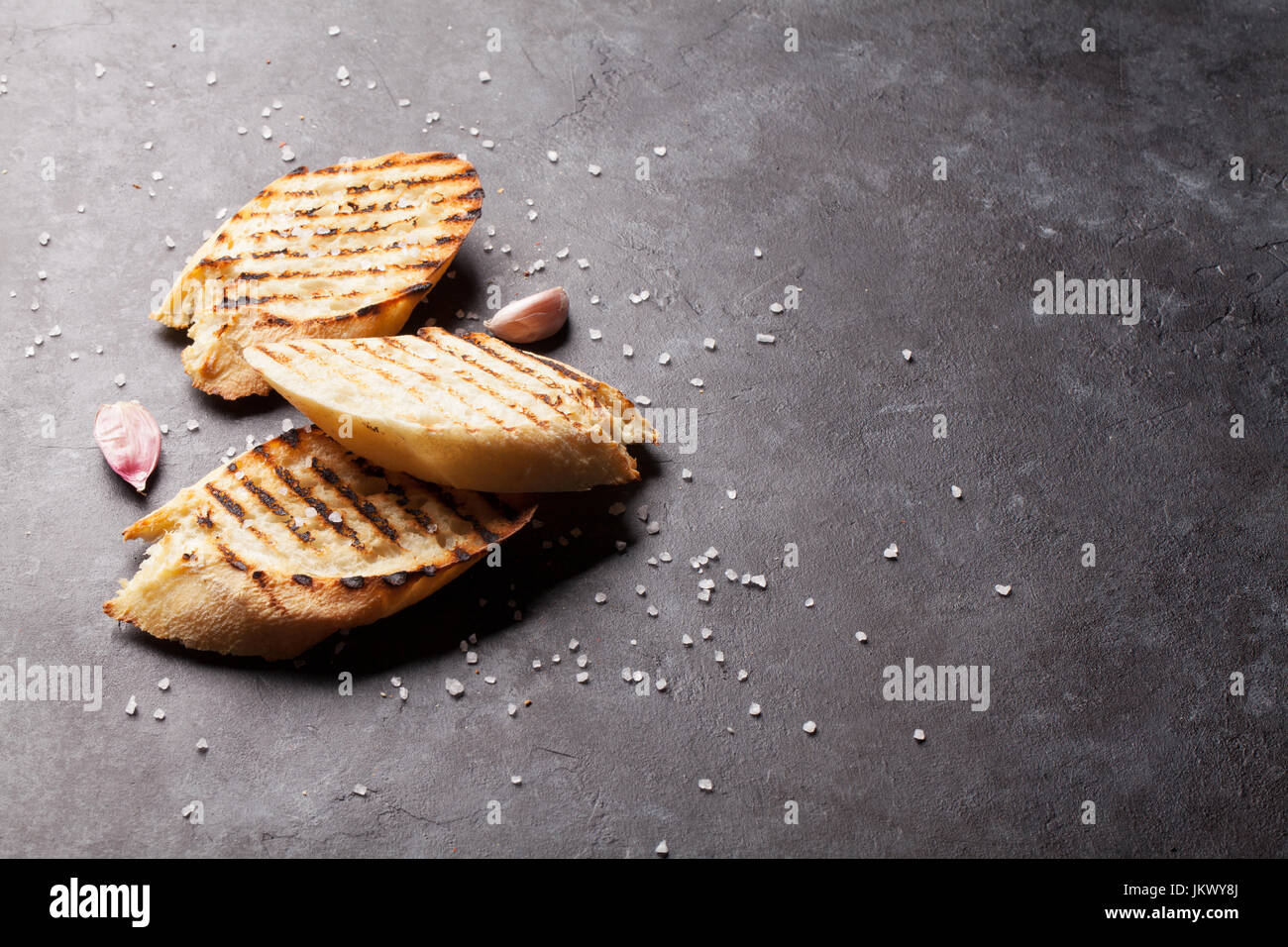 Toast bread with salt and garlic on stone table. View with copy space ...