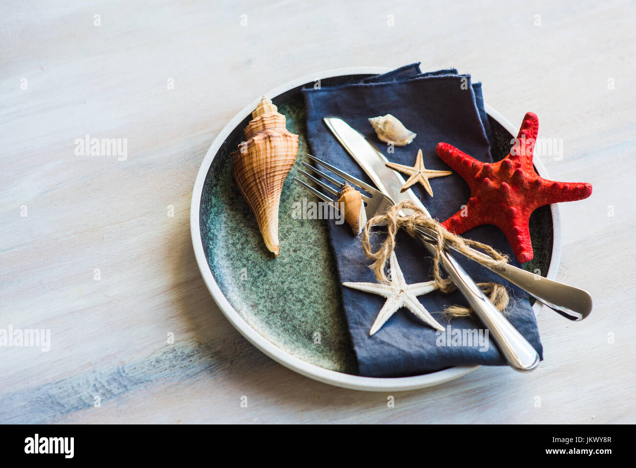 Summer vacation marine table setting with rustic plates and silverware ...