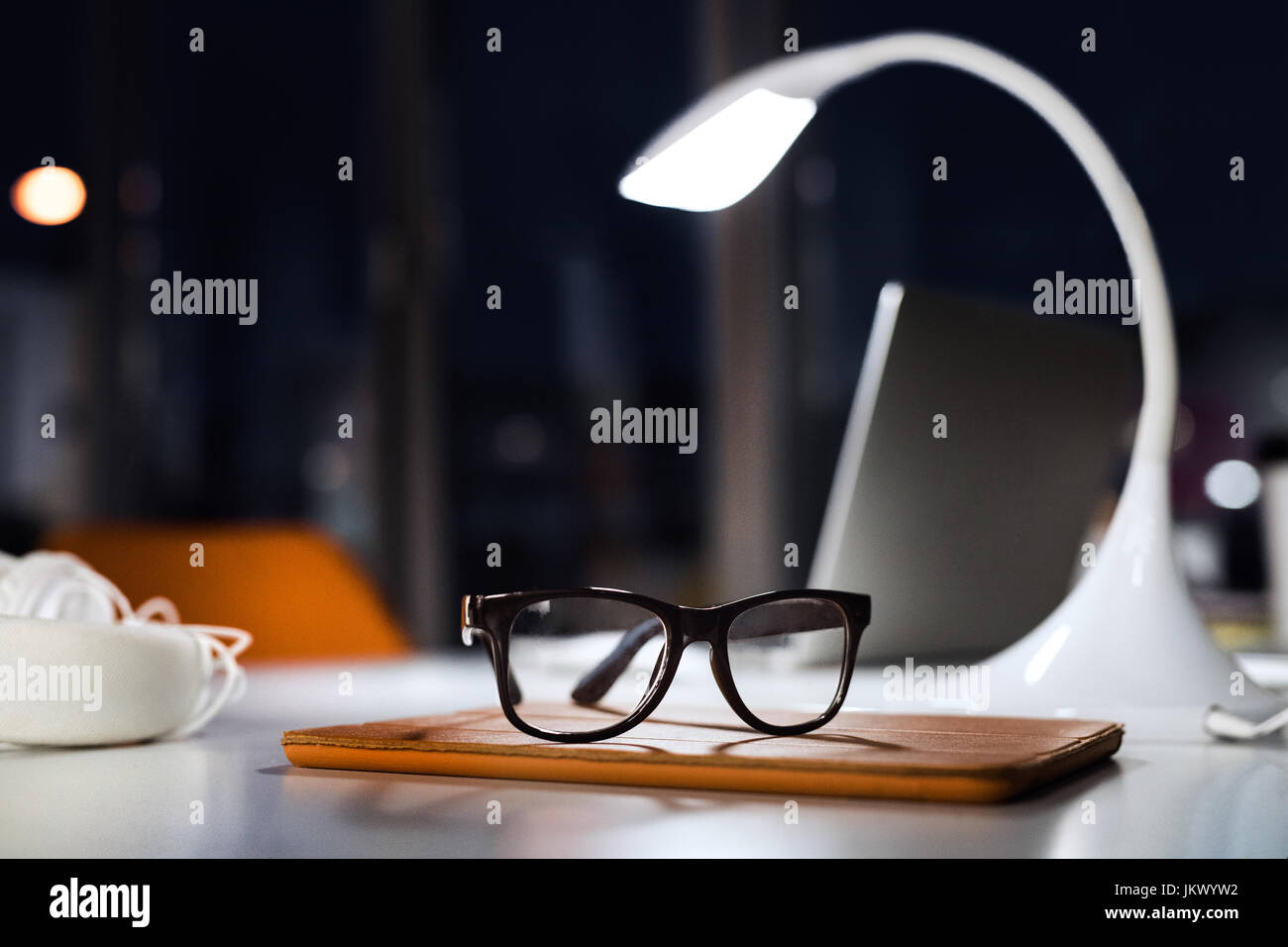 Office desk at night with eyeglasses, lamp and tablet Stock Photo - Alamy