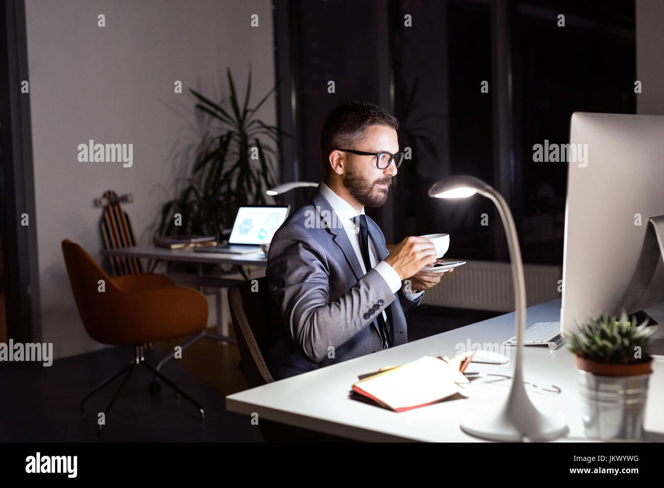 Businessman in the office at night drinking coffee Stock Photo - Alamy