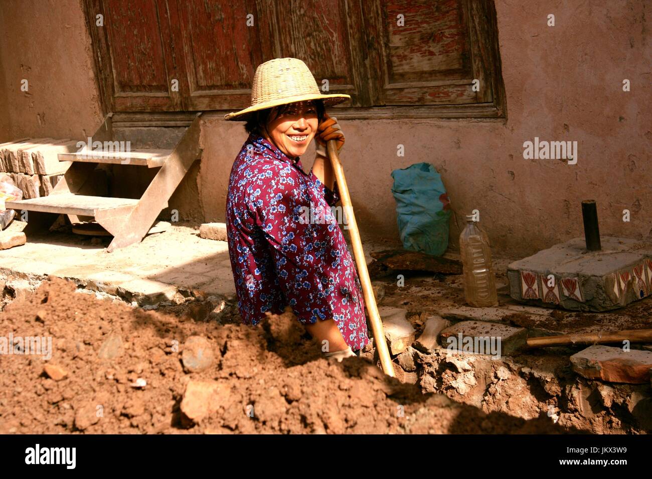 Chinese lady digging a trench in old town Urumqi Stock Photo - Alamy
