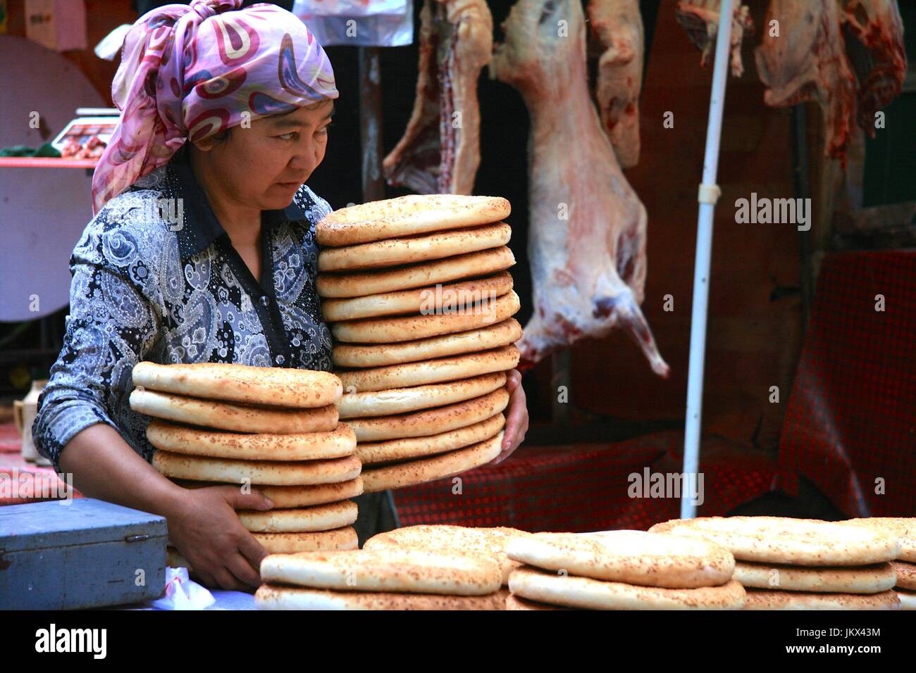 Woman carrying a stack of pita bread for sale in old town Urumqi Stock ...