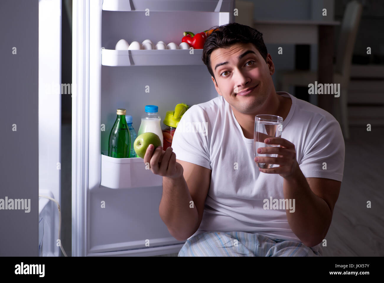 Man at the fridge eating at night Stock Photo - Alamy