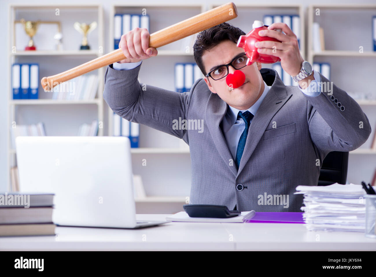 Clown businessman with a baseball bat and a piggy bank Stock Photo - Alamy