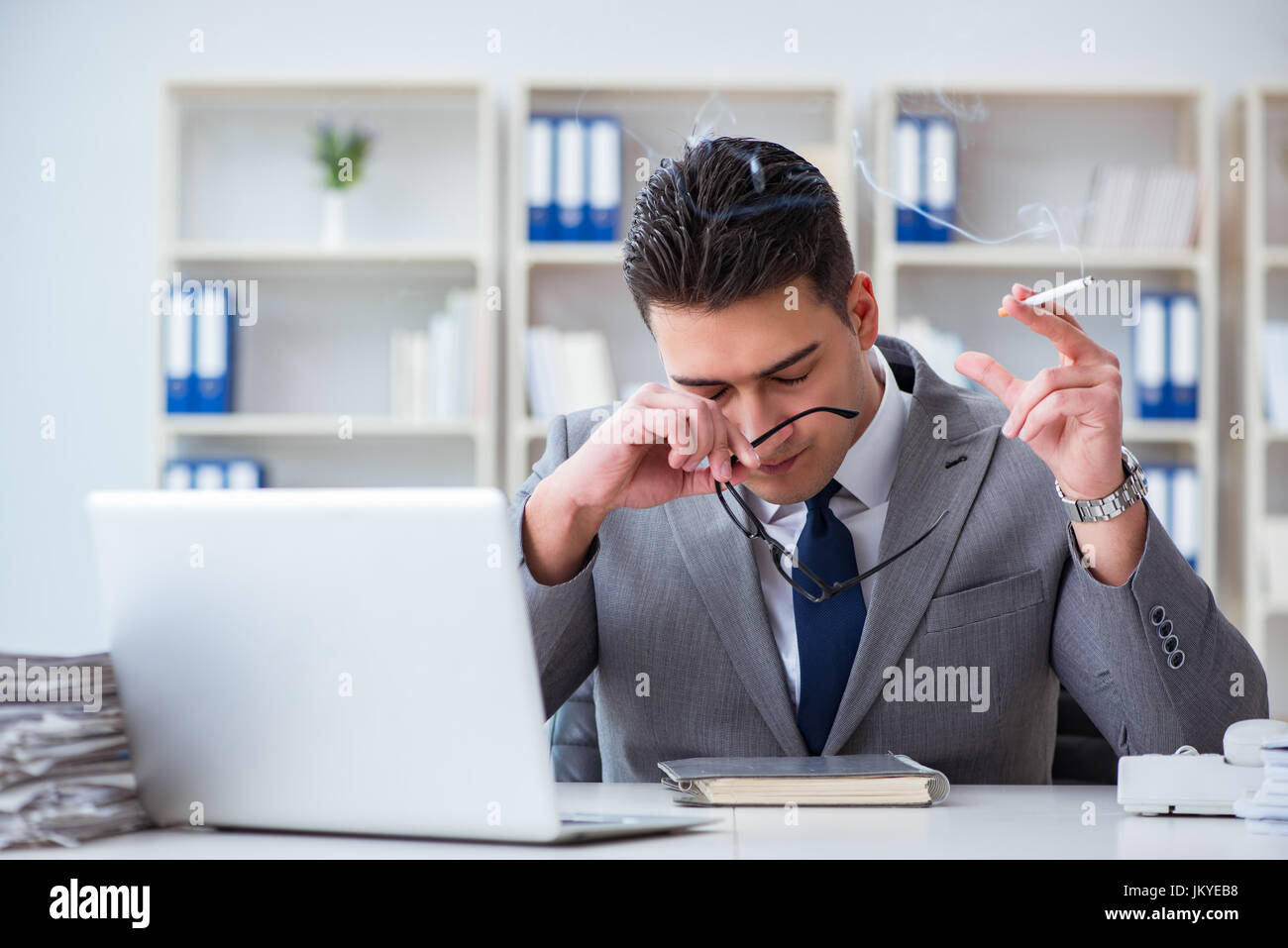 Businessman smoking in office at work Stock Photo - Alamy