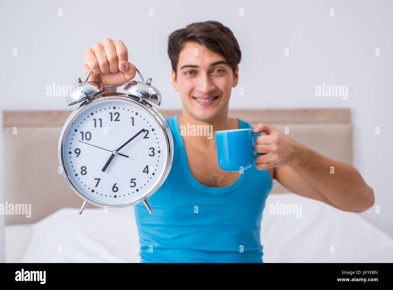 Young man waking up in bed Stock Photo - Alamy