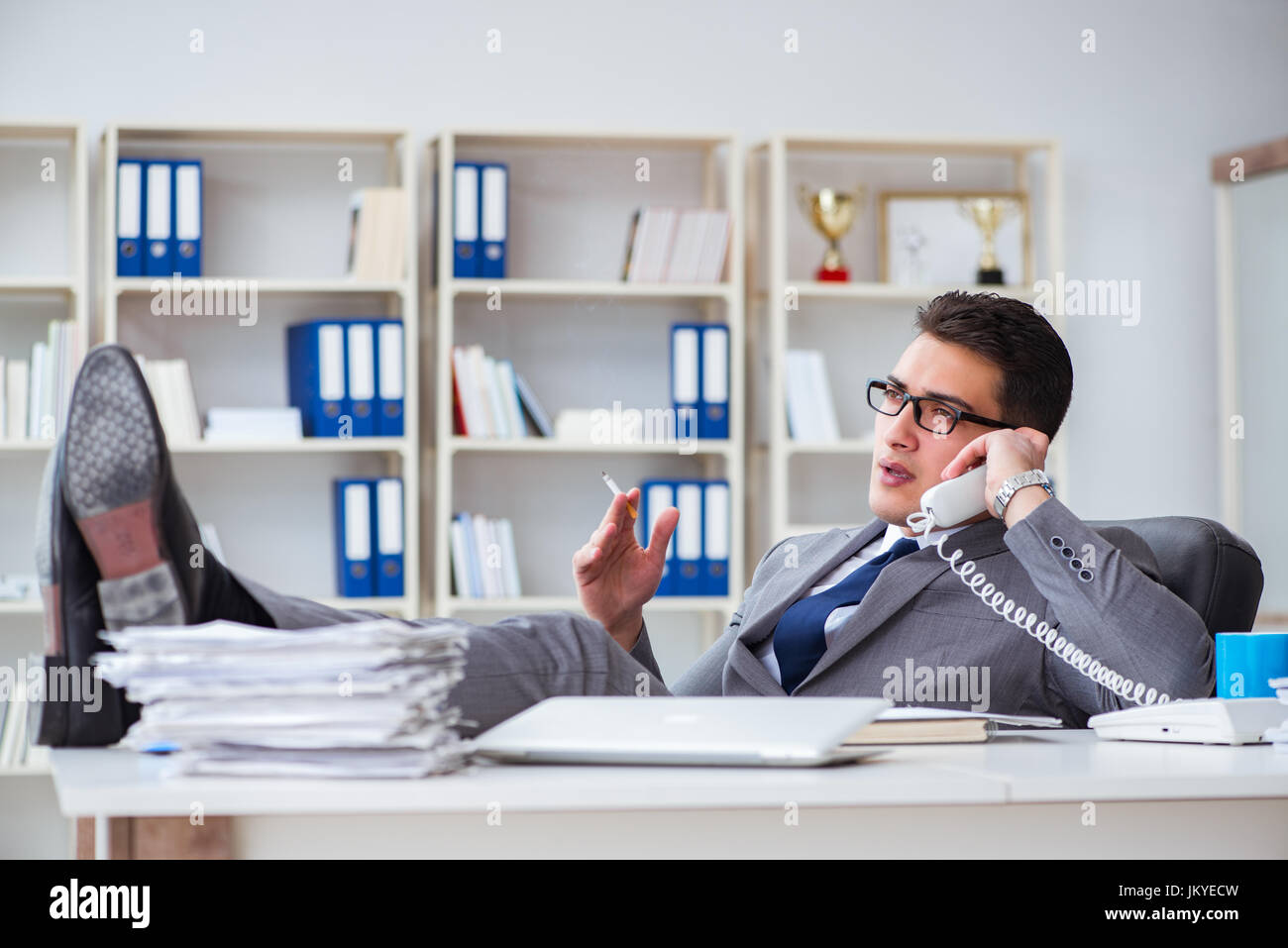 Businessman smoking in office at work Stock Photo - Alamy