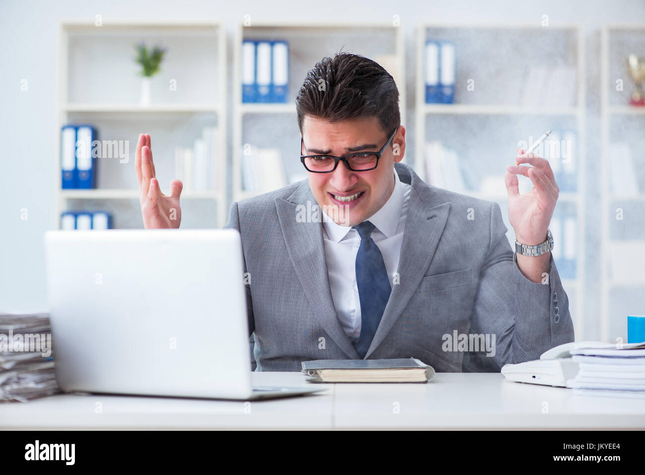 Businessman smoking in office at work Stock Photo - Alamy