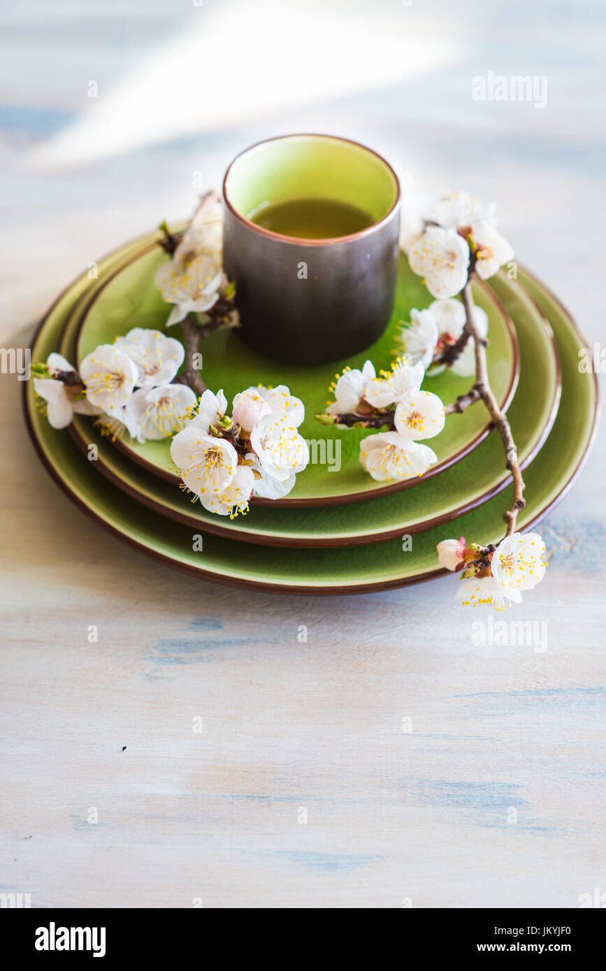 Cup of green tea and peach blossom on dark rustic table as a spring ...