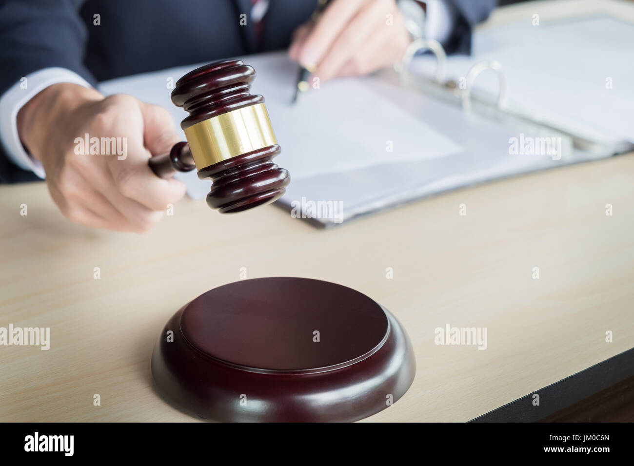 Male Judge In A Courtroom Striking The Gavel on sounding block Stock ...