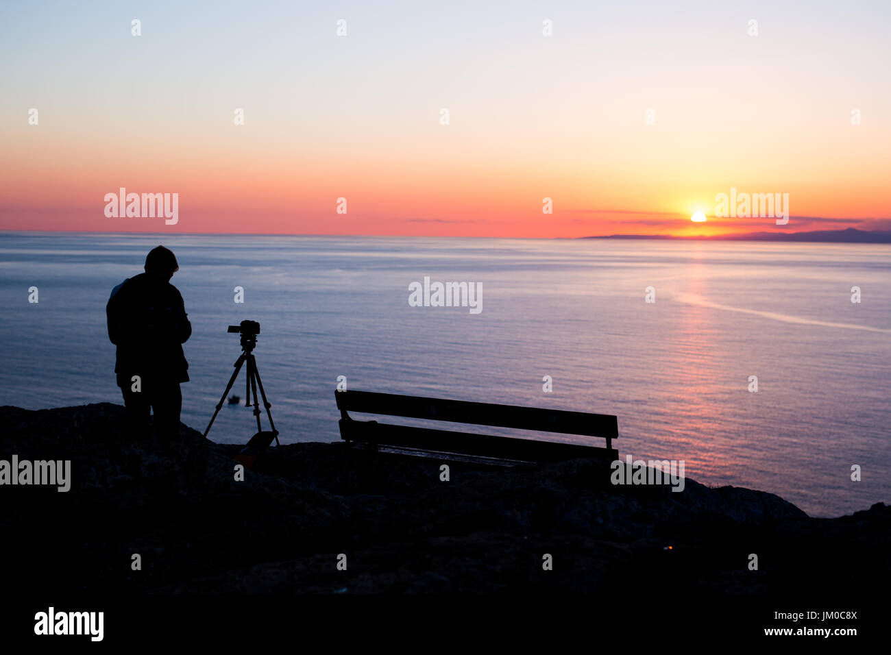 man photographer taking photos of sunset at the sea Stock Photo - Alamy