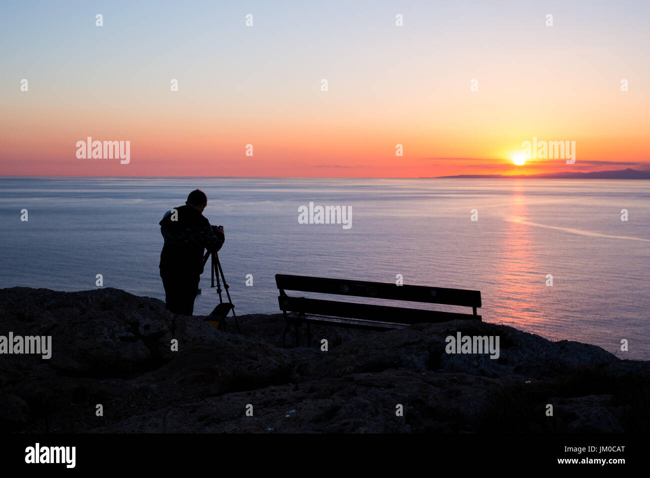 man photographer taking photos of sunset at the sea Stock Photo - Alamy
