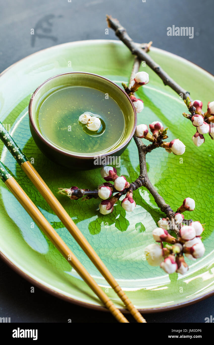 Cup of green tea and peach blossom on dark rustic table as a spring ...