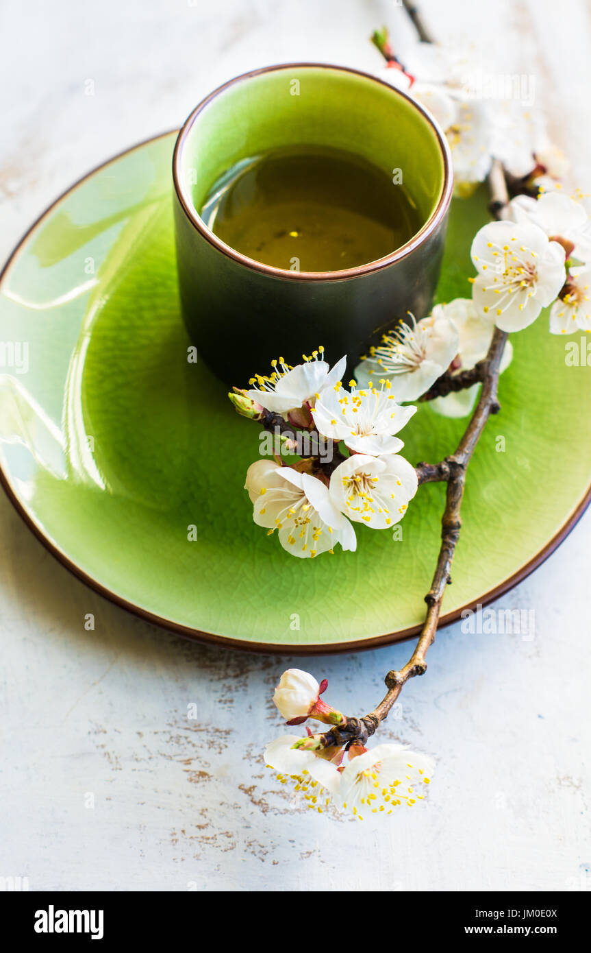 Cup of green tea and peach blossom on dark rustic table as a spring ...