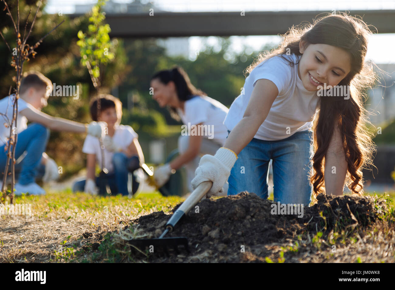 Sunny day. Positive delighted girl bowing her head and keeping smile on ...