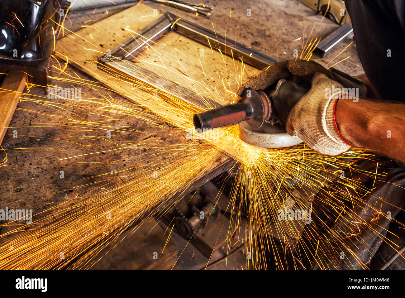 A close-up of a strong man with hardened hands welds a metal welding ...