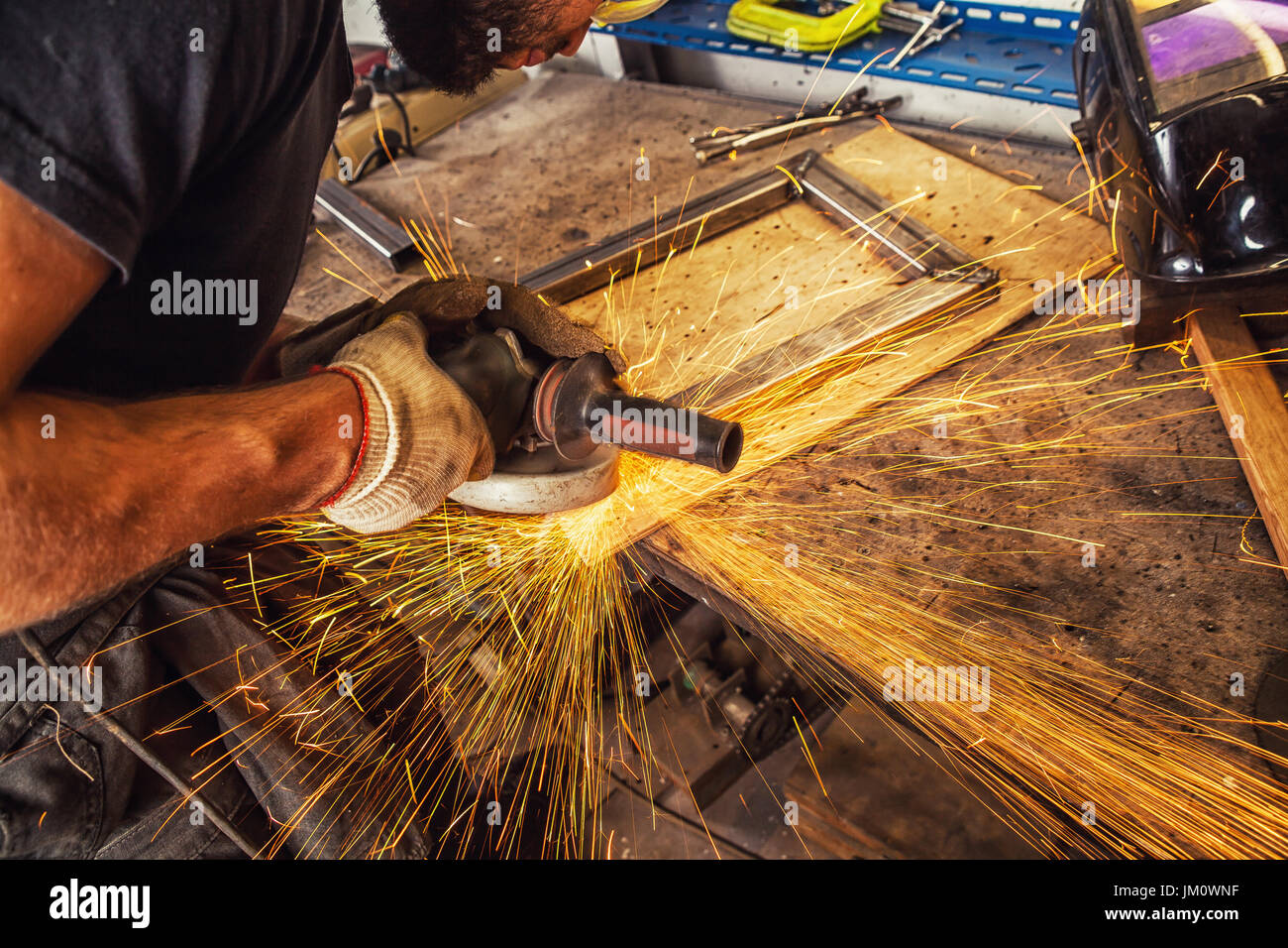 A close-up of a strong man with hardened hands welds a metal welding ...