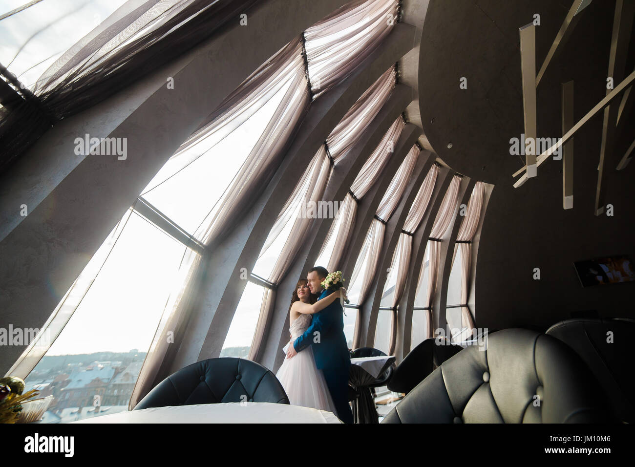 Horizontal view of the hugging newlywed couple looking through the ...