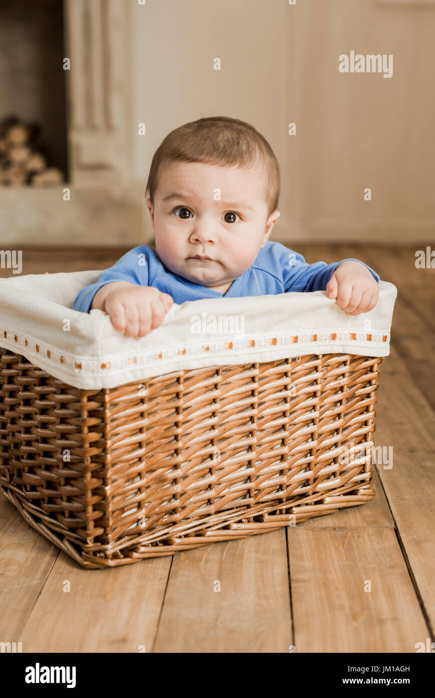 Portrait of adorable little baby boy sitting inside of braided box and ...