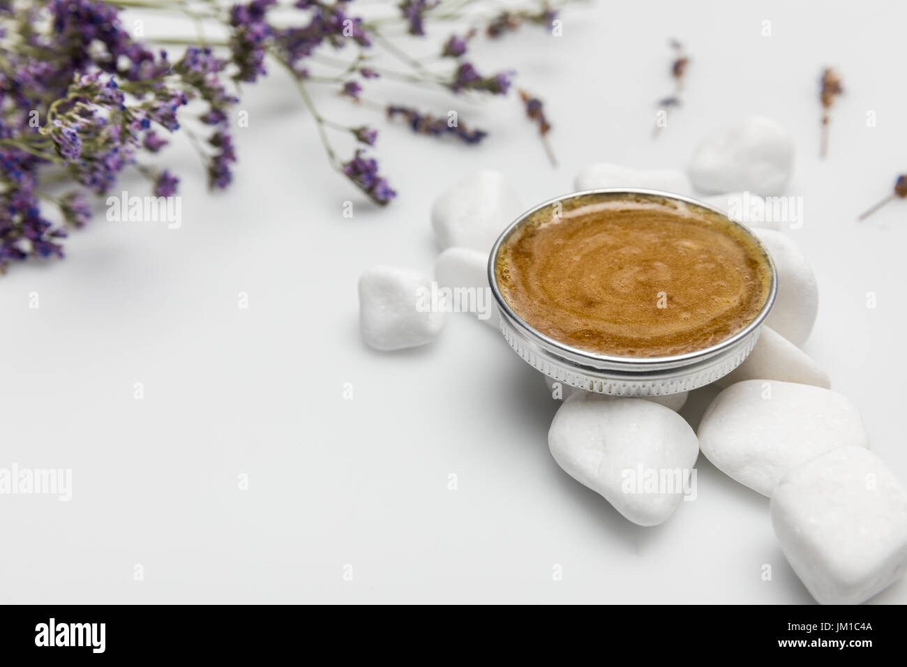 Close-up view of organic scrub in container and dried lavender isolated ...