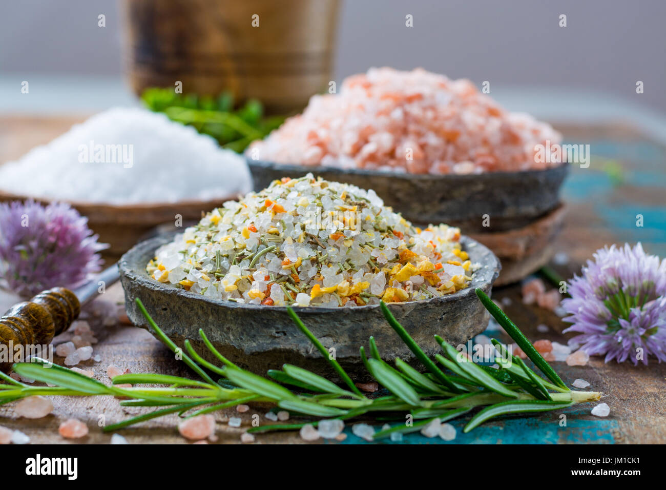 Different types of natural salt in stone bowls on wooden surface. White ...