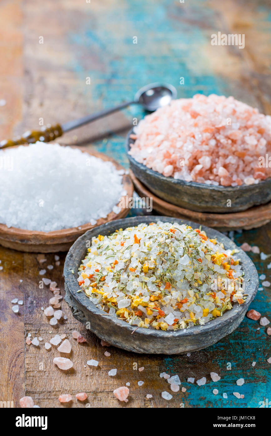 Different types of natural salt in stone bowls on wooden surface. White ...