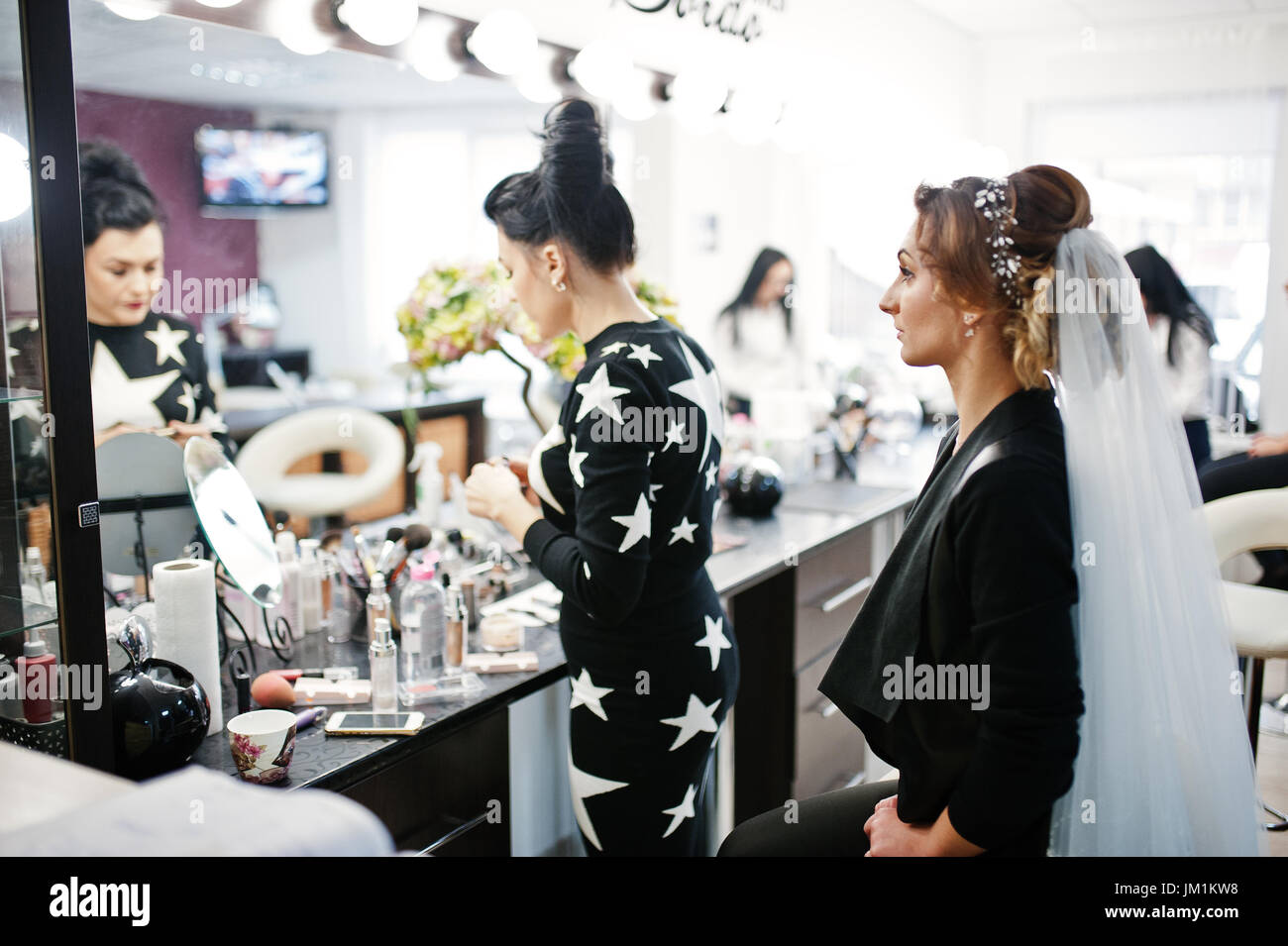 Gorgeous bride having her hair and makeup done in the beauty salon ...
