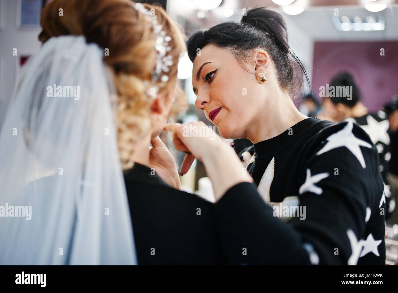 Gorgeous bride having her hair and makeup done in the beauty salon ...