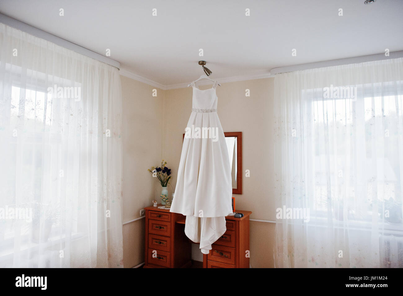Wedding dress hanging on the rack in the room Stock Photo - Alamy