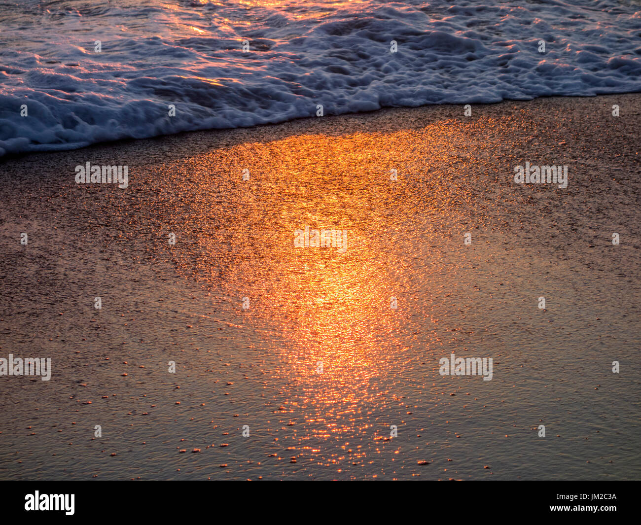 Sunset reflecting on Atlantic beach Stock Photo - Alamy