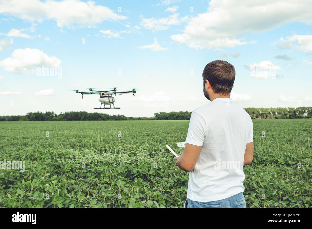 Young man operating of flying drone octocopter at the green field Stock ...
