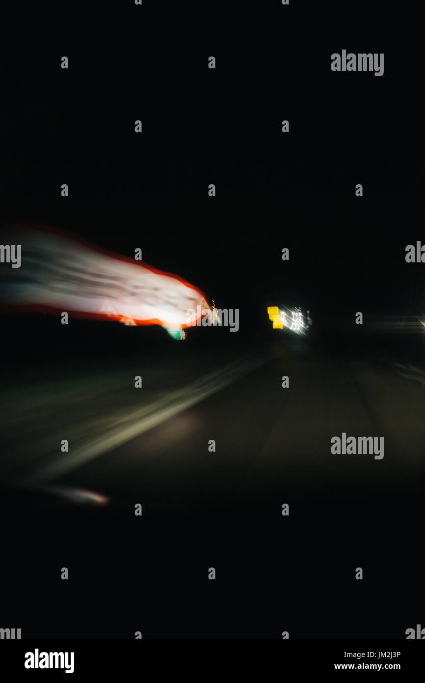 View from a fast moving car at night with a blurred speed limit sight ...