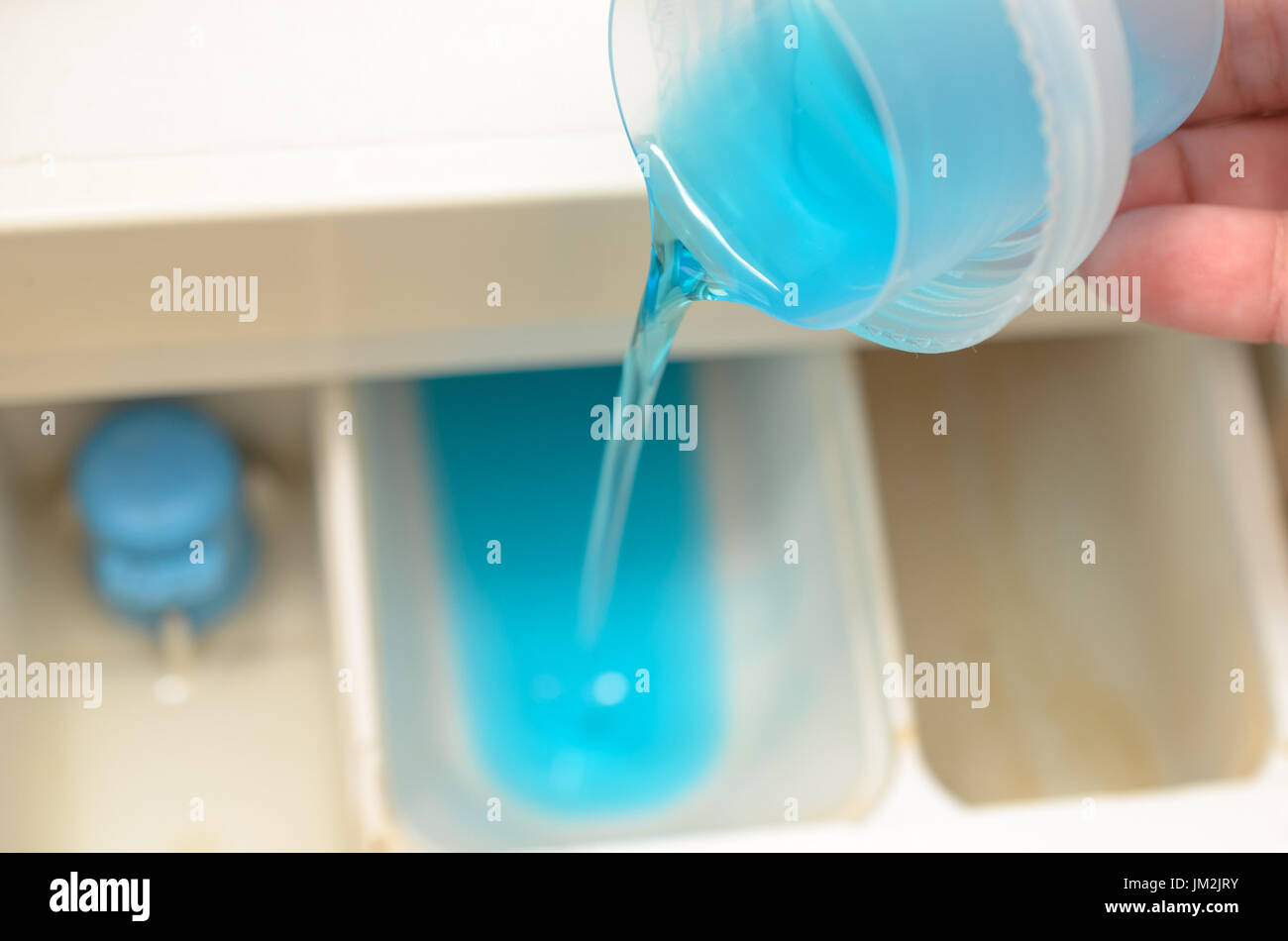 A blue detergent is poured into the washing container Stock Photo - Alamy