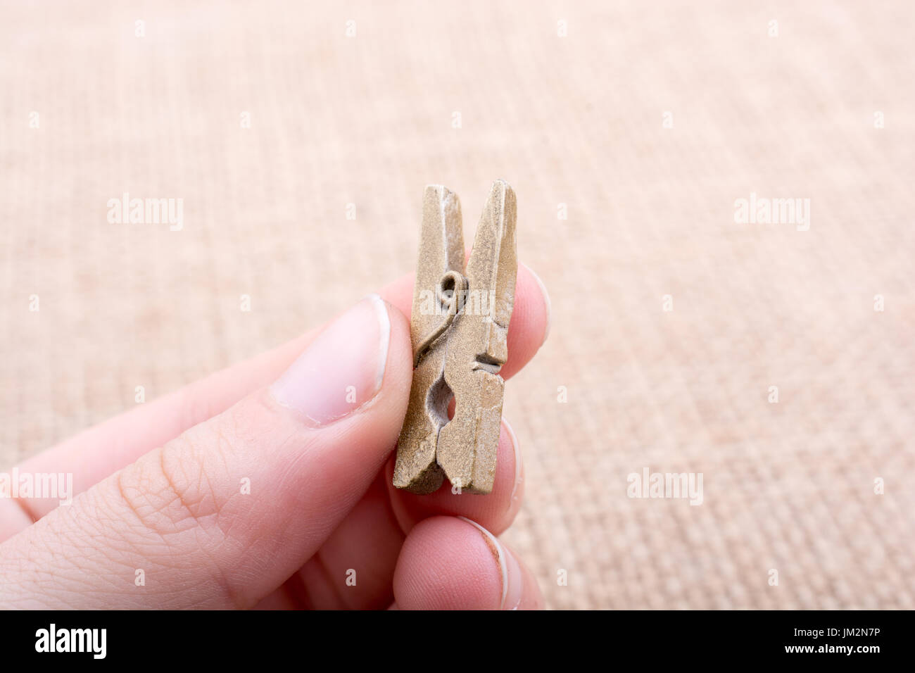 Hand holding a small wooden clothespin in hand Stock Photo - Alamy