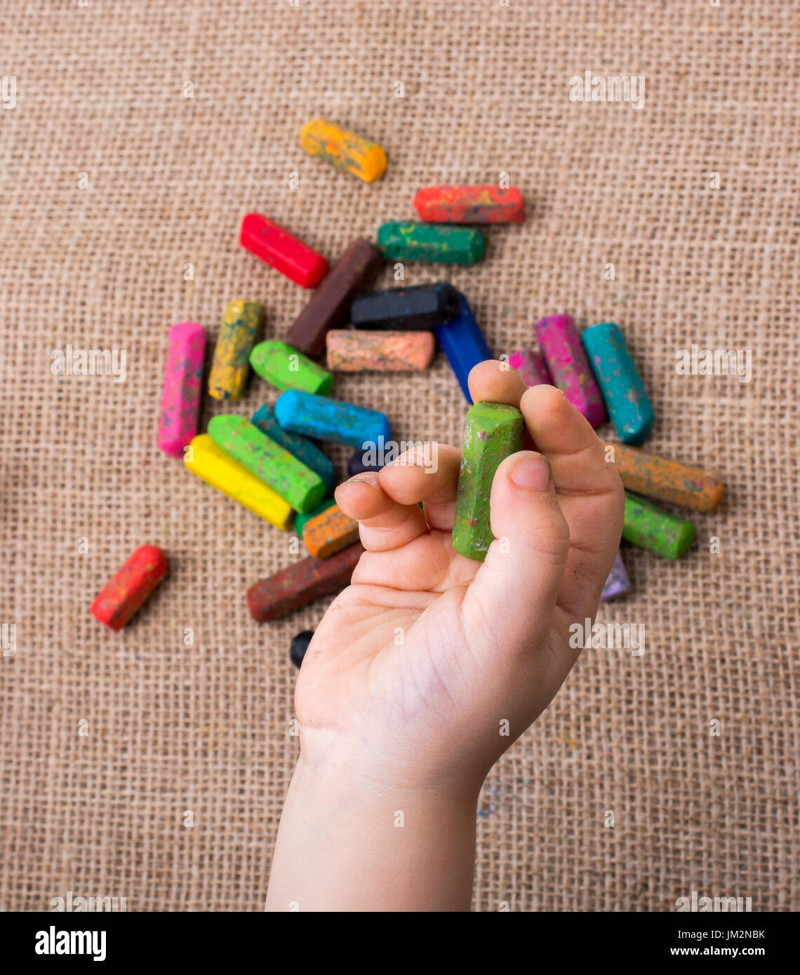 Used color crayons and a toddlers hand holding one Stock Photo - Alamy