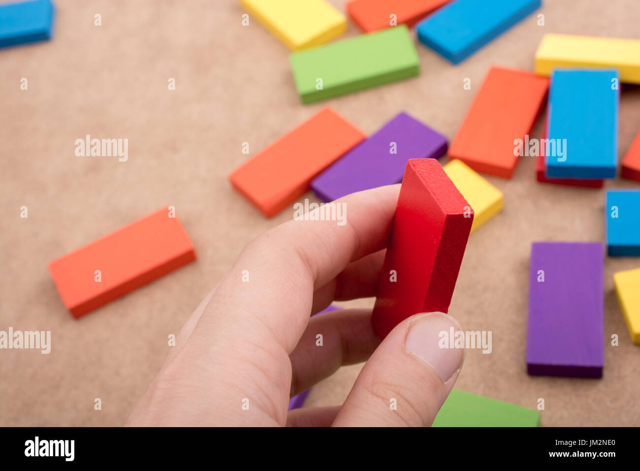 Hand holding one of the wooden blocks of various colors Stock Photo - Alamy